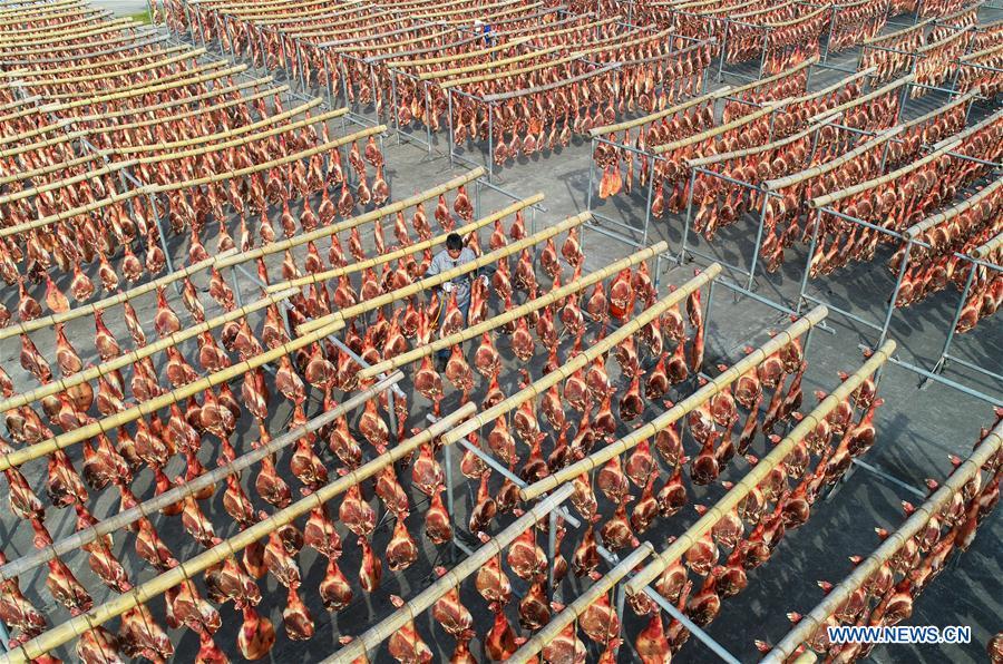Staff workers dry hams through traditional methods in Jinhua